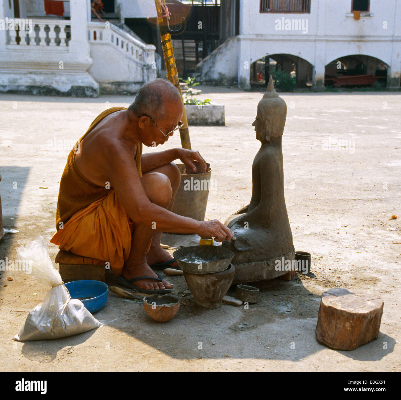 A monk is modelizing a Buddha statue out of plaster Luang Prabang Laos ...