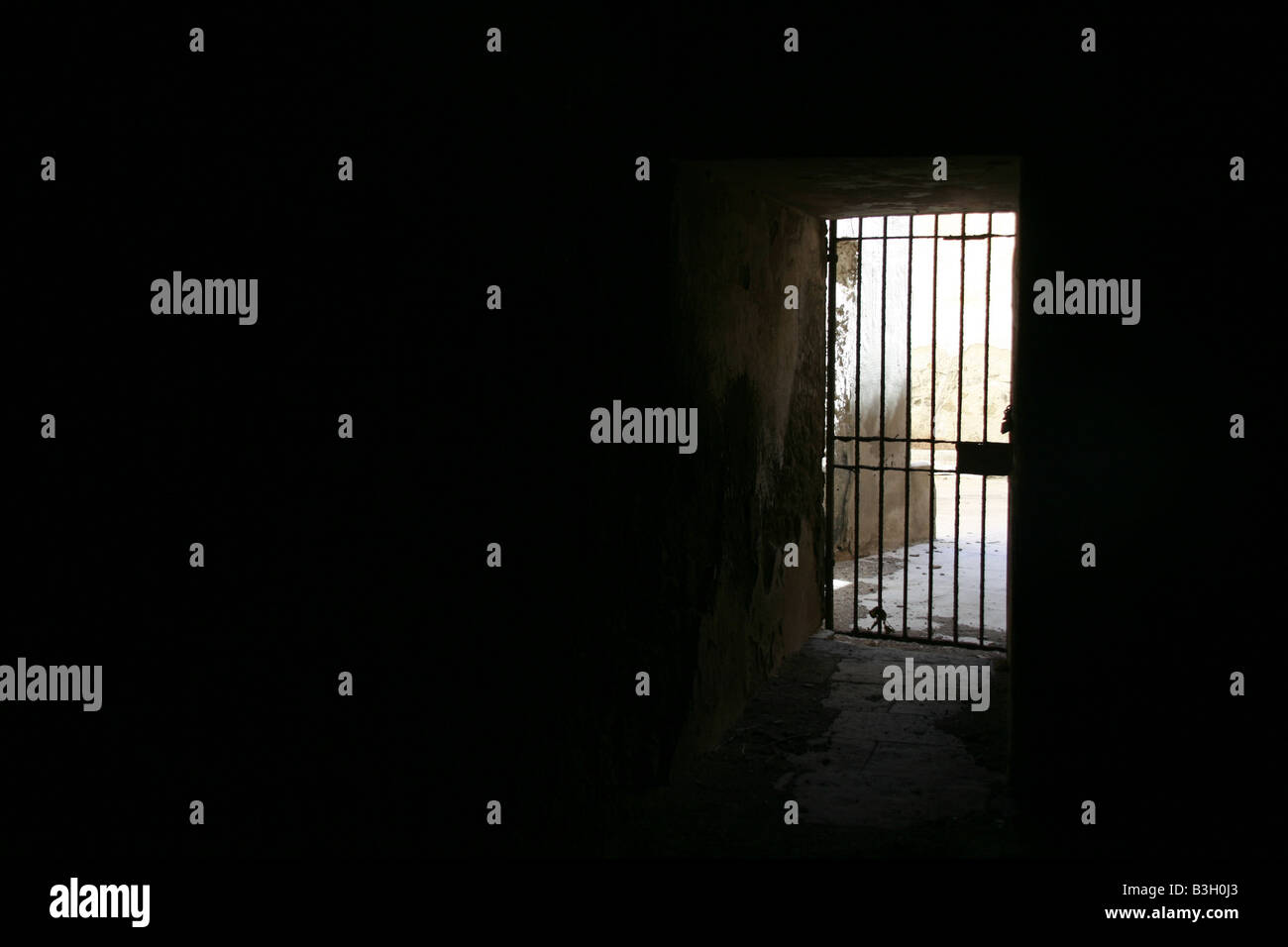 one secluded prison cell door in dark black room Stock Photo - Alamy