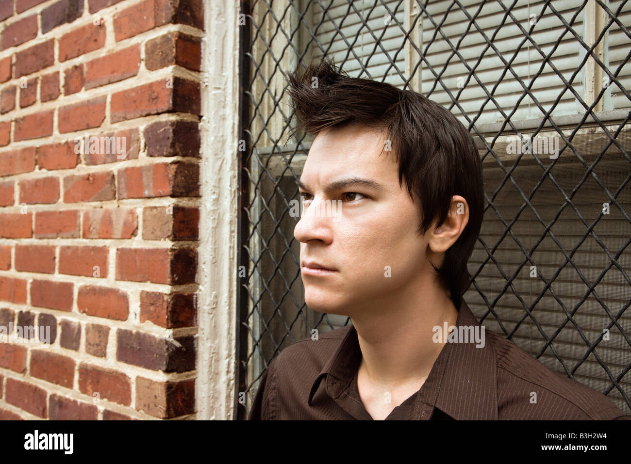 Asian man leaning against window near brick wall Stock Photo - Alamy