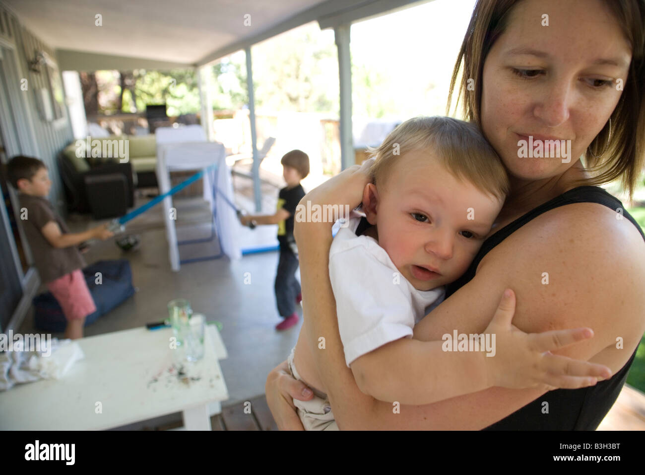 worried mother holds infant while older siblings play sword battles in ...