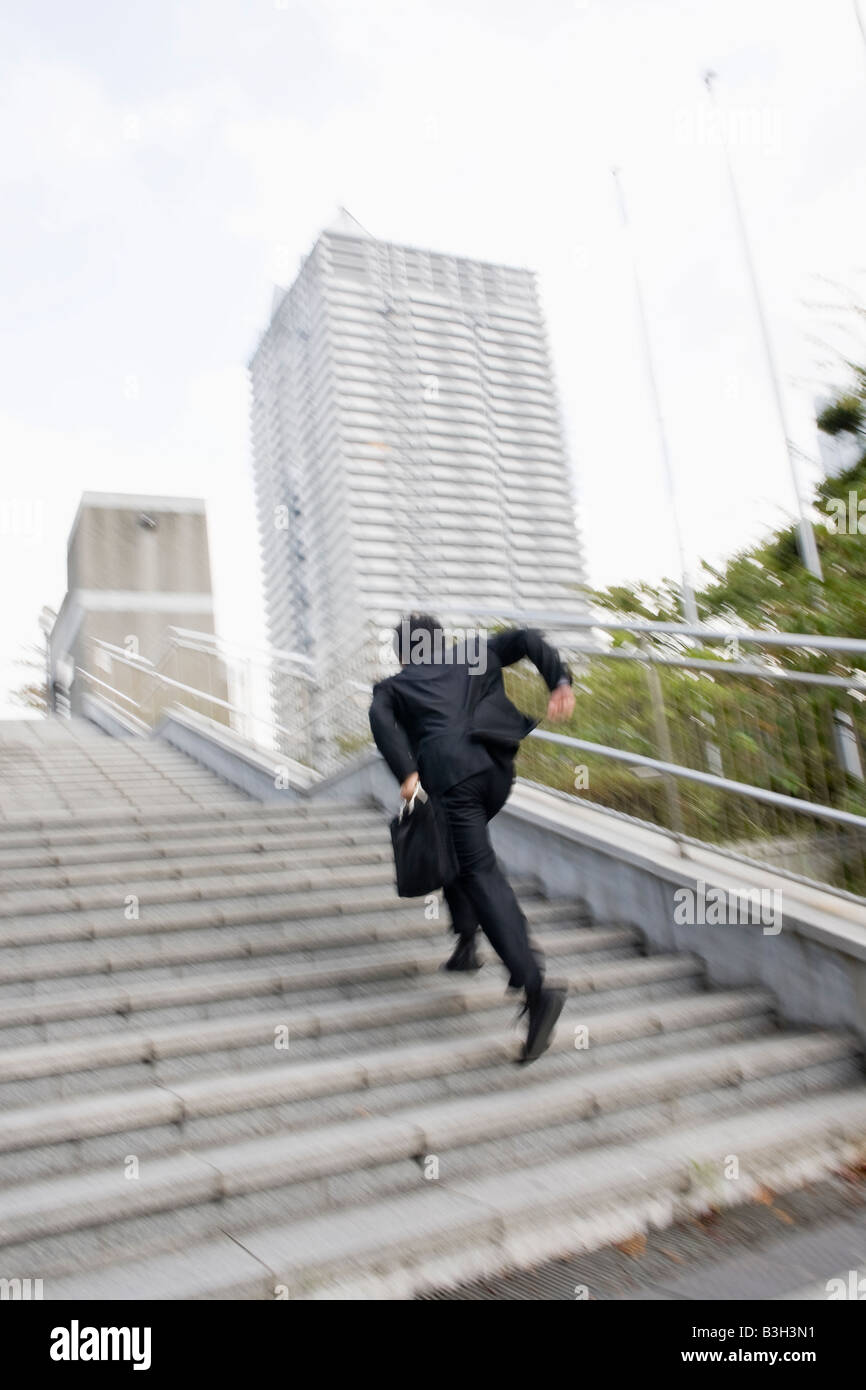 Businessman running up steps Stock Photo - Alamy