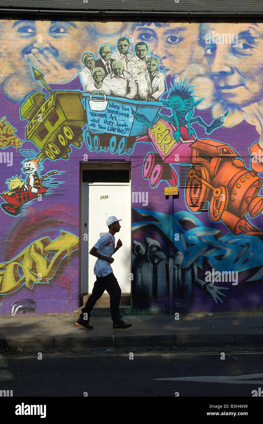 A boy running passed a wall covered with graffiti in east Oxford Stock ...