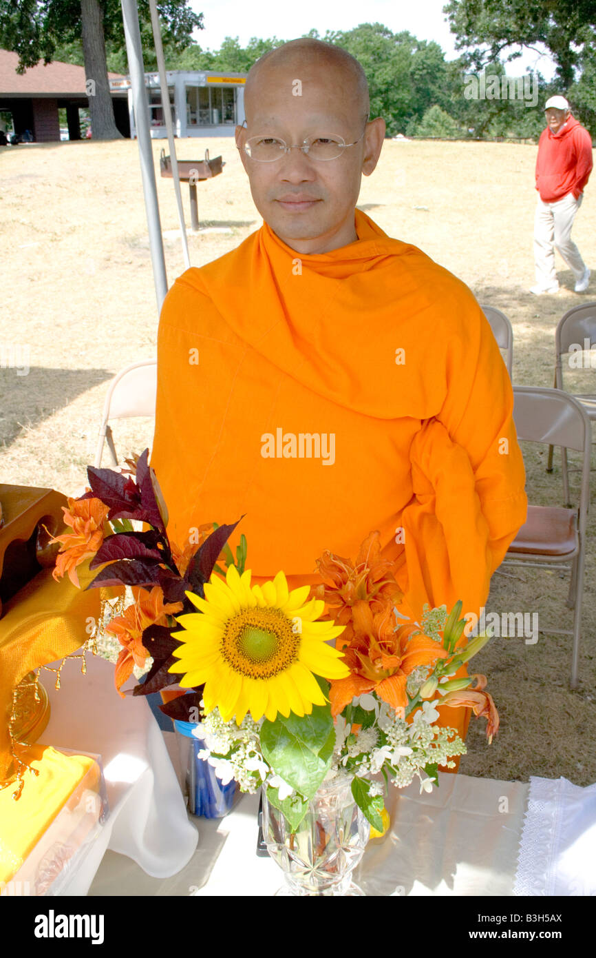 Buddhist monk standing by bouquet orange tiger lilies and a sunflower ...