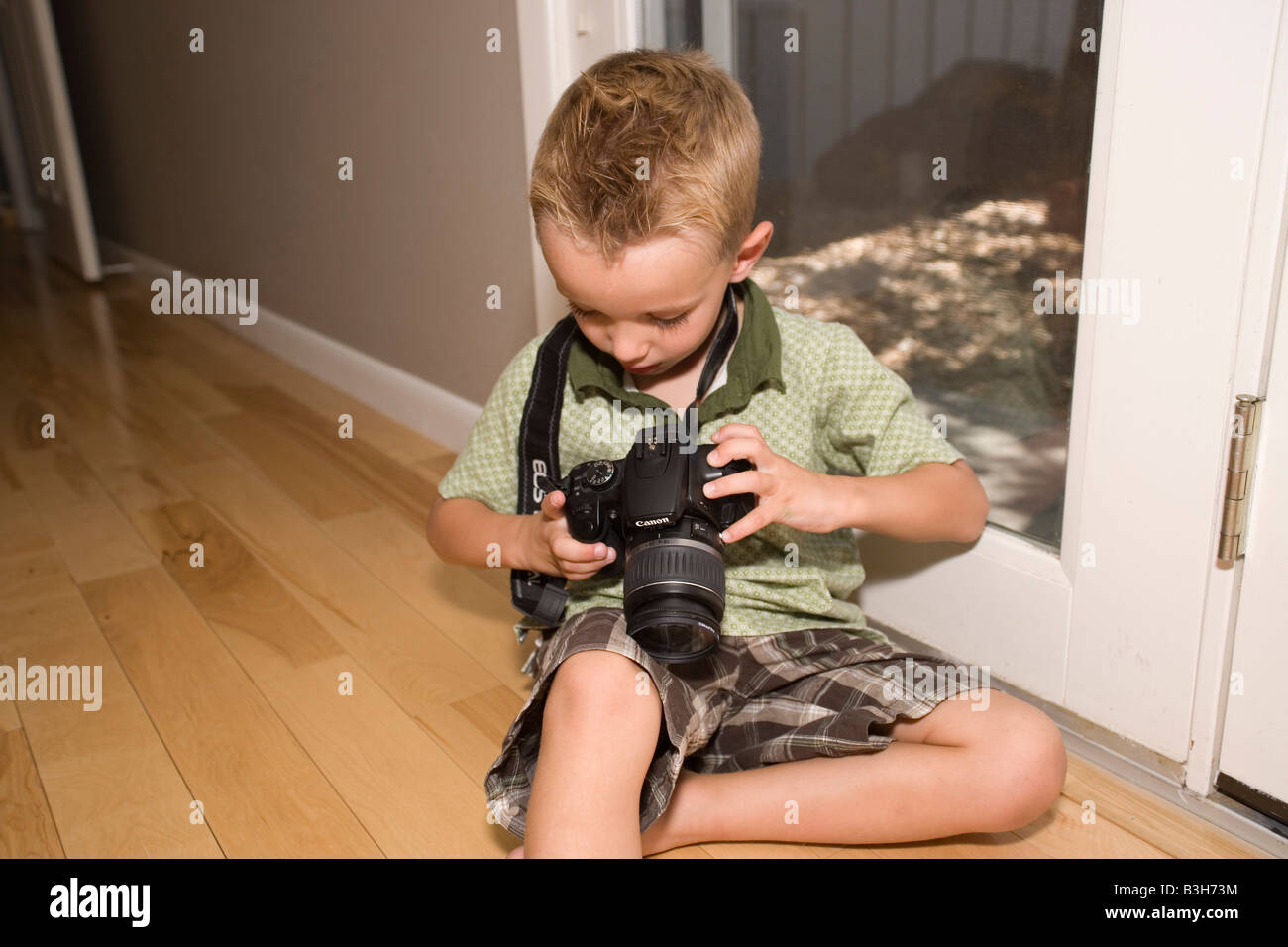 four year old boy adjusts digital camera as he learns how to take ...