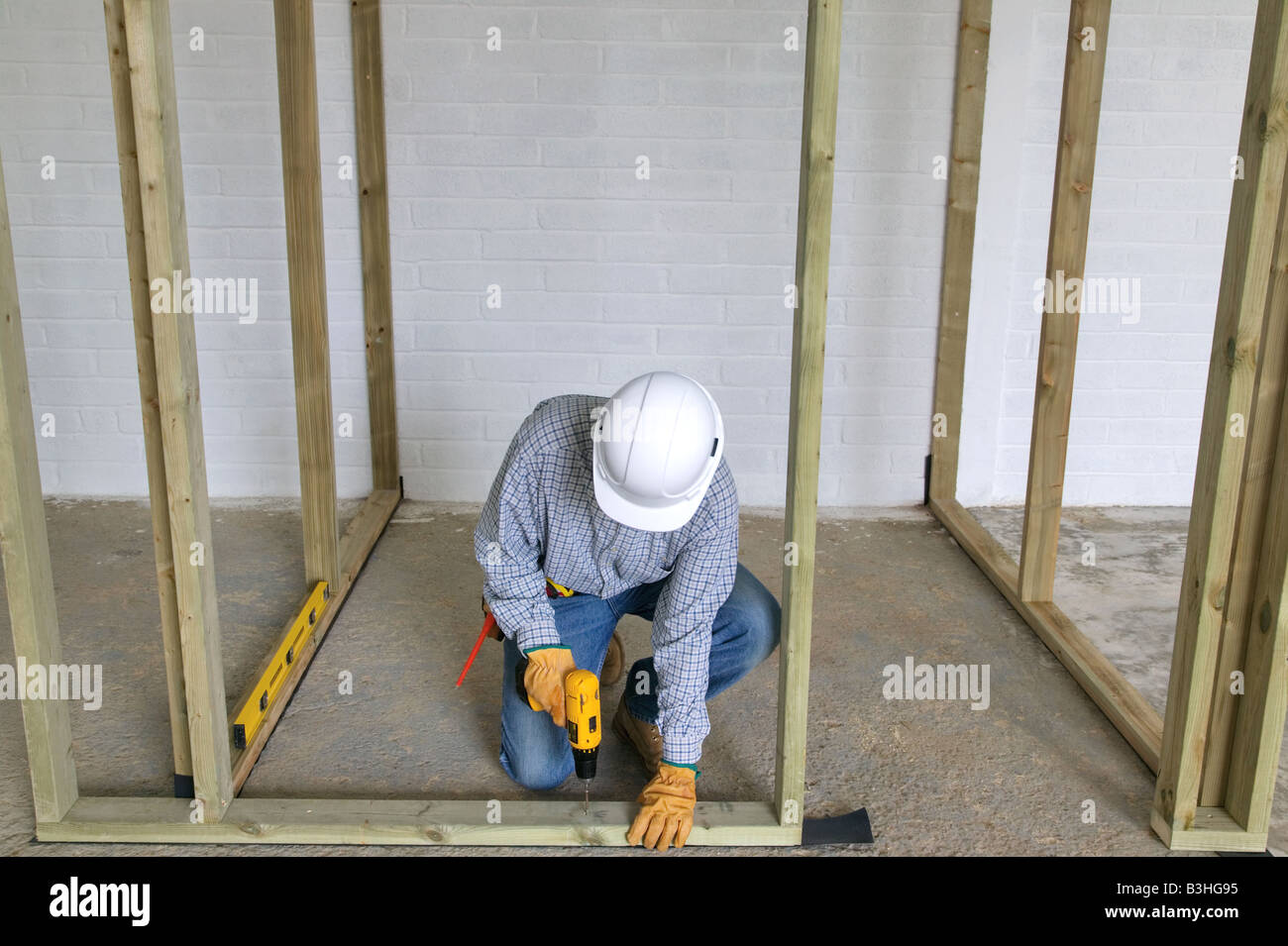 Carpenter fixing a timber framework into a concrete floor Stock Photo ...