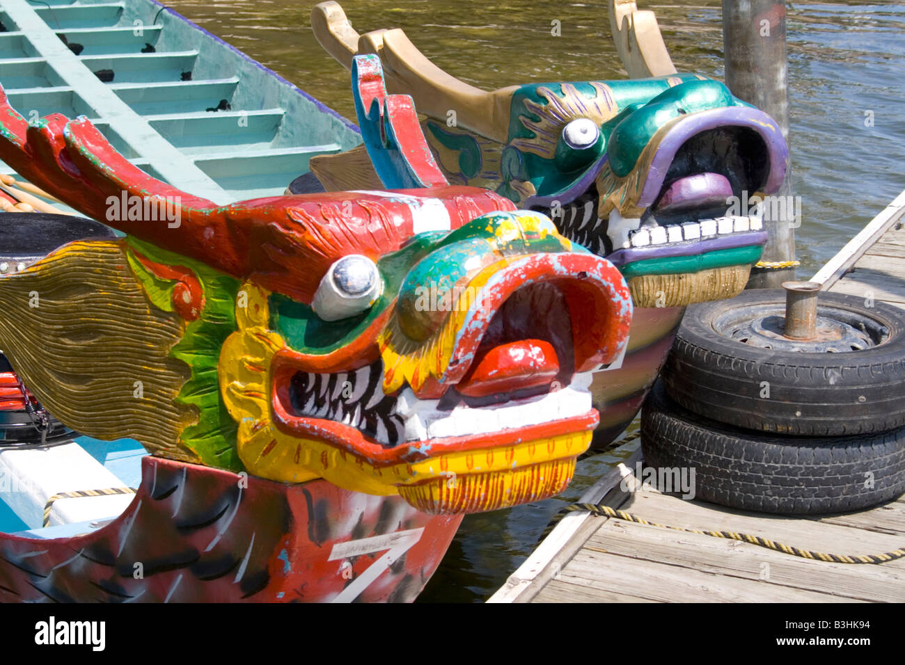 Fierce Asian dragon heads on bow of racing boats moored at dock. Dragon ...