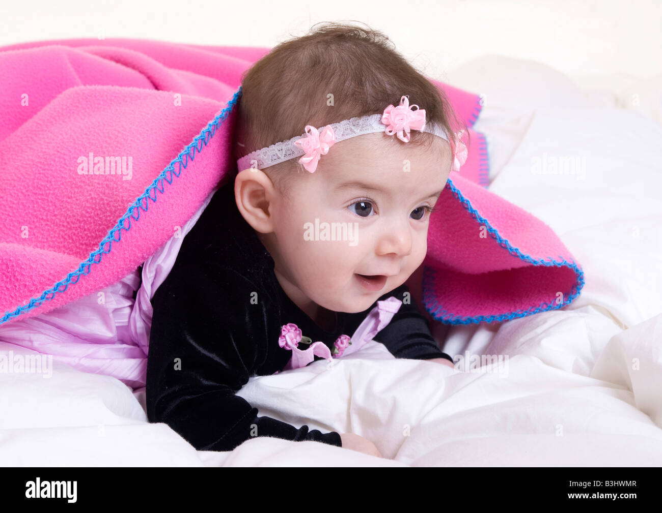 A young infant looking out from under a blanket Stock Photo - Alamy