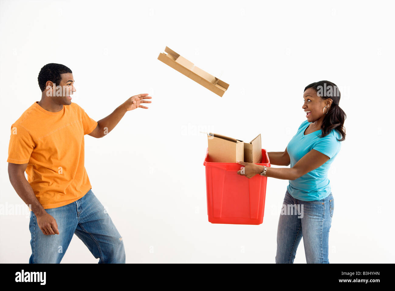 African American female holding recycling bin while male tosses ...