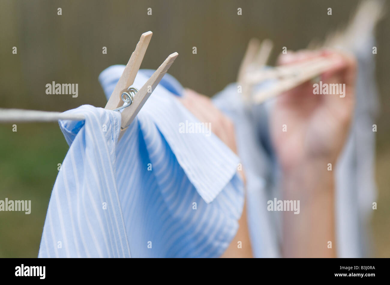 Close-up of a young woman's hands hanging clothes to dry on a line ...