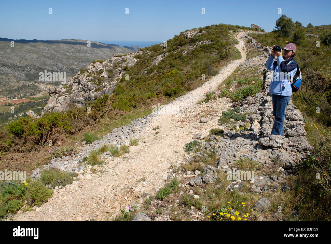 woman hiker taking a photo, on ridge of Sierra de la Forada, Alicante ...