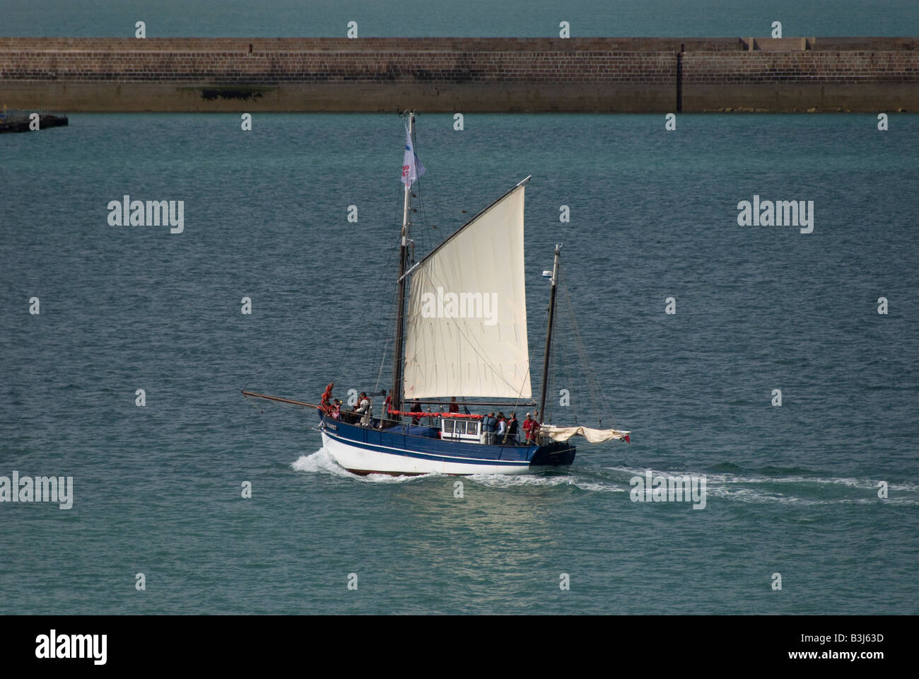 A gaff-rigged ketch sailing out of Cherbourg harbour, Normandy, France ...