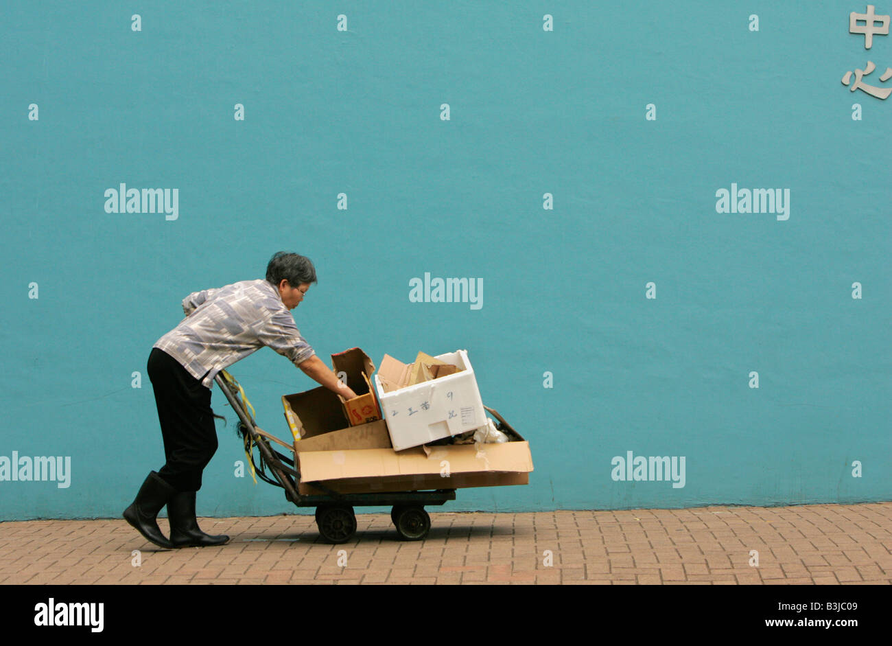 An old woman rubbish collector (freelance recycling) pushing a loaded ...
