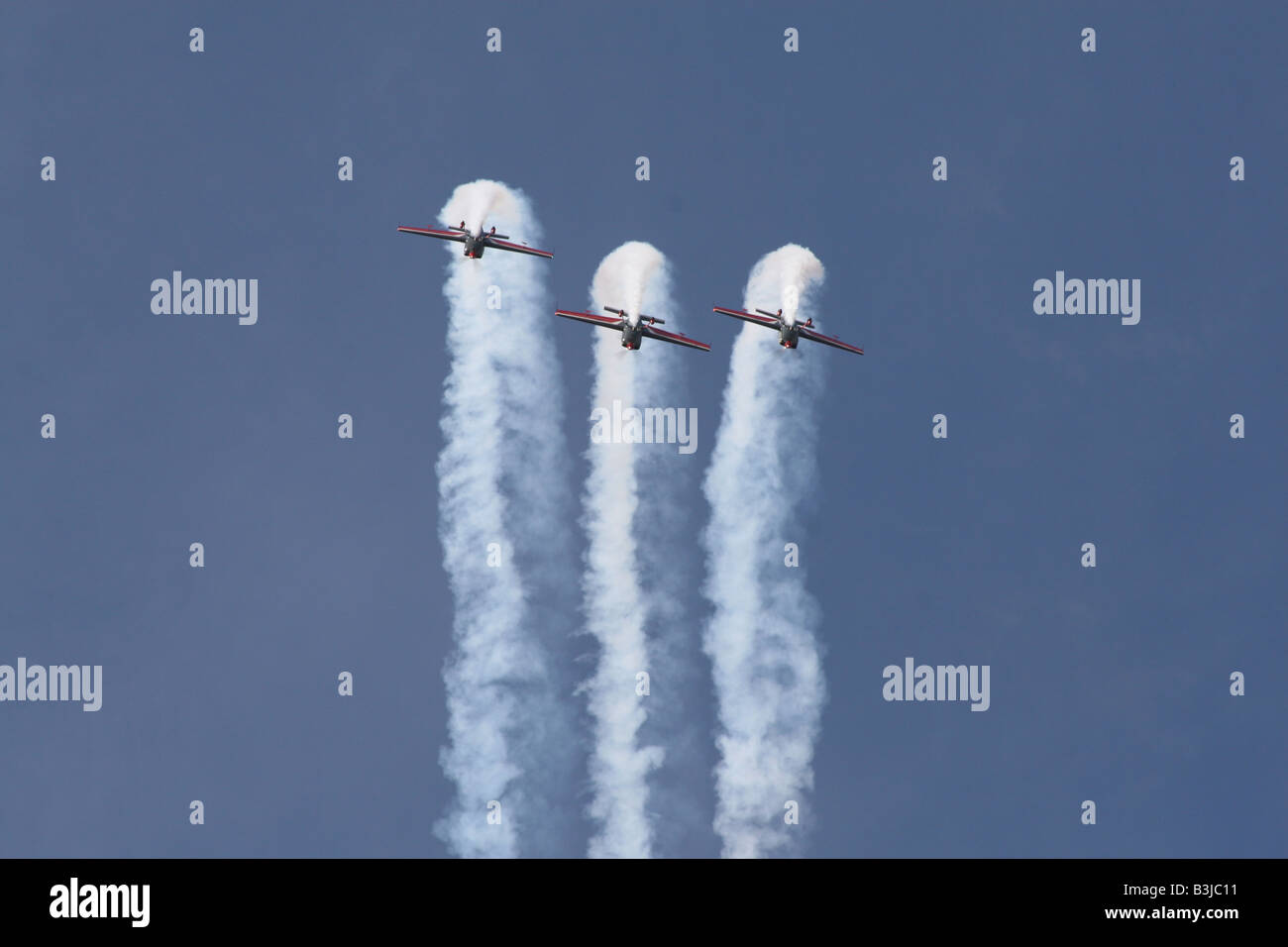 three aircraft looping in formation with smoke trails against blue sky ...