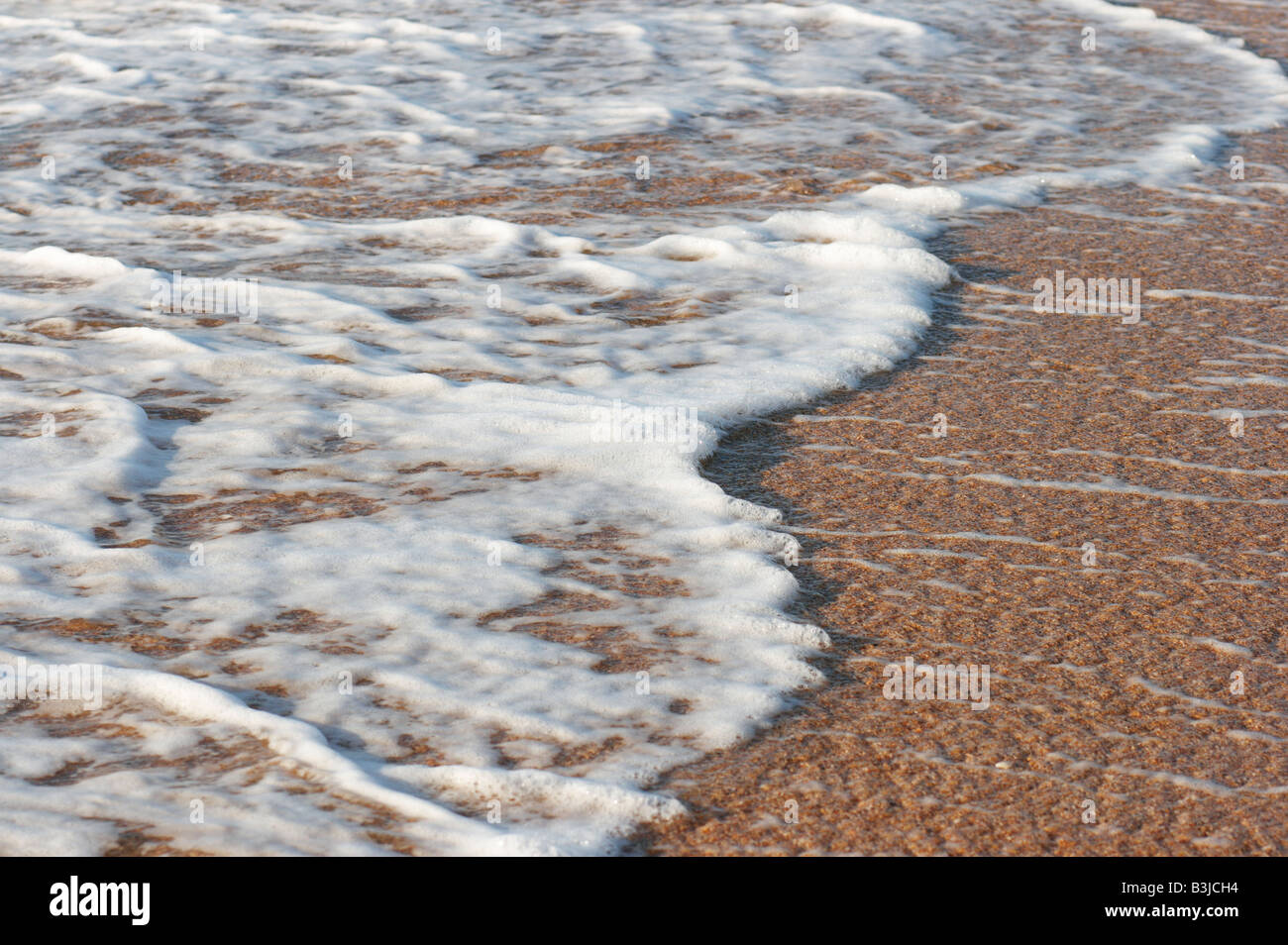 Sea surf foam on coastline sand Stock Photo - Alamy