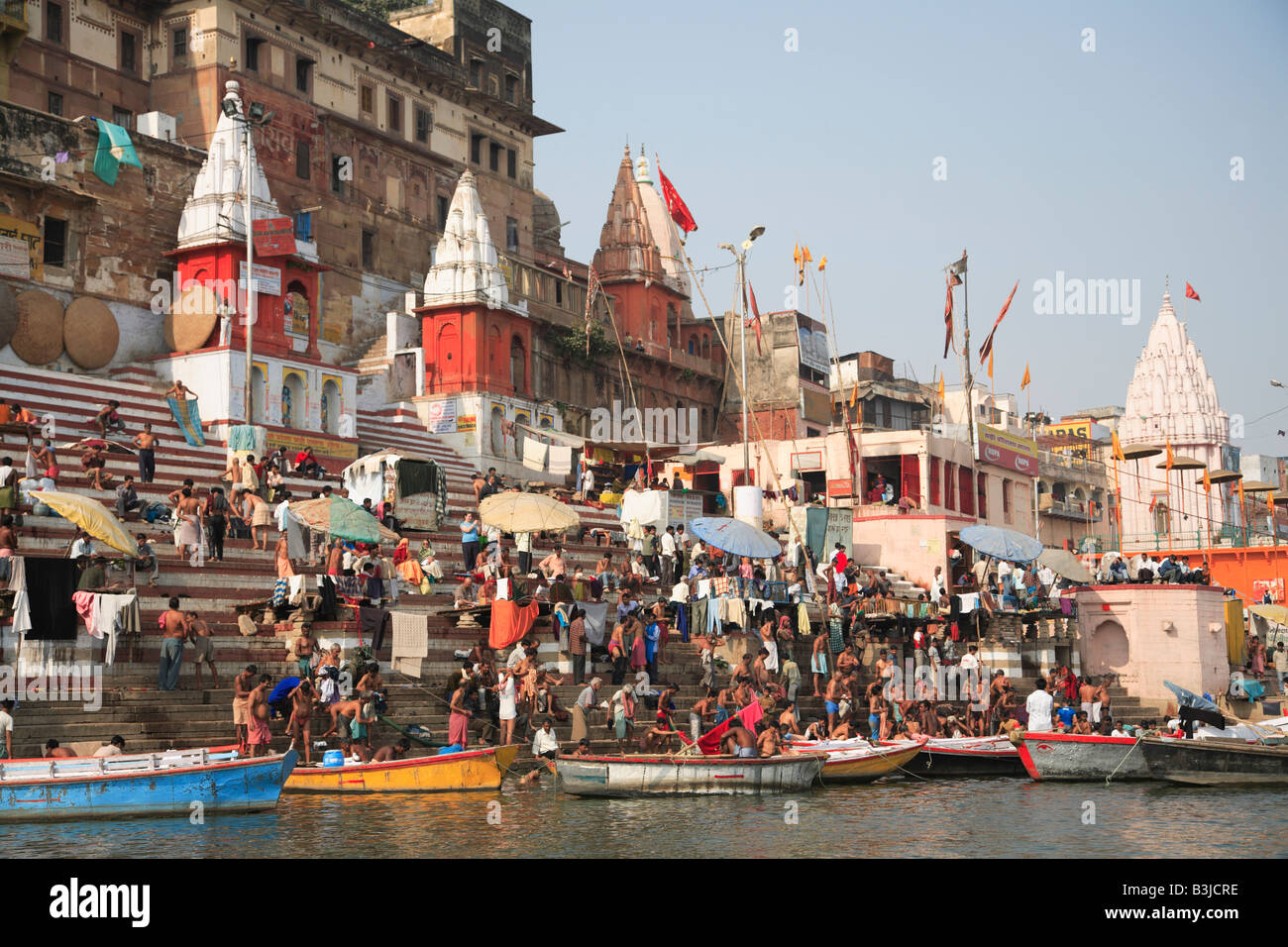 Religious Hindu Pilgrims in the Ganges River lined with ghats steps and ...