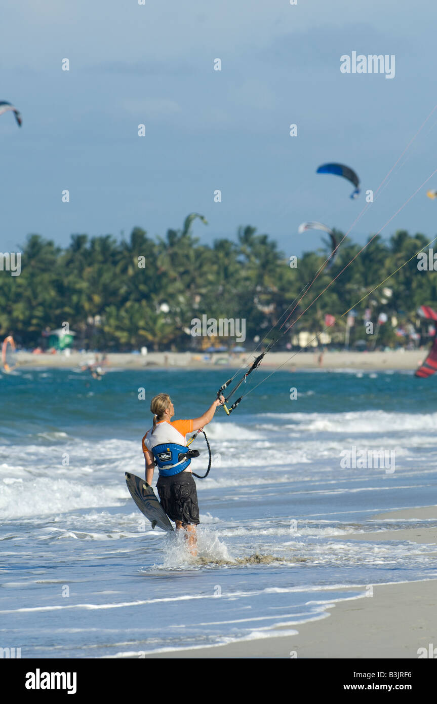 A young woman walks her kite and board along Cabarete beach in the ...