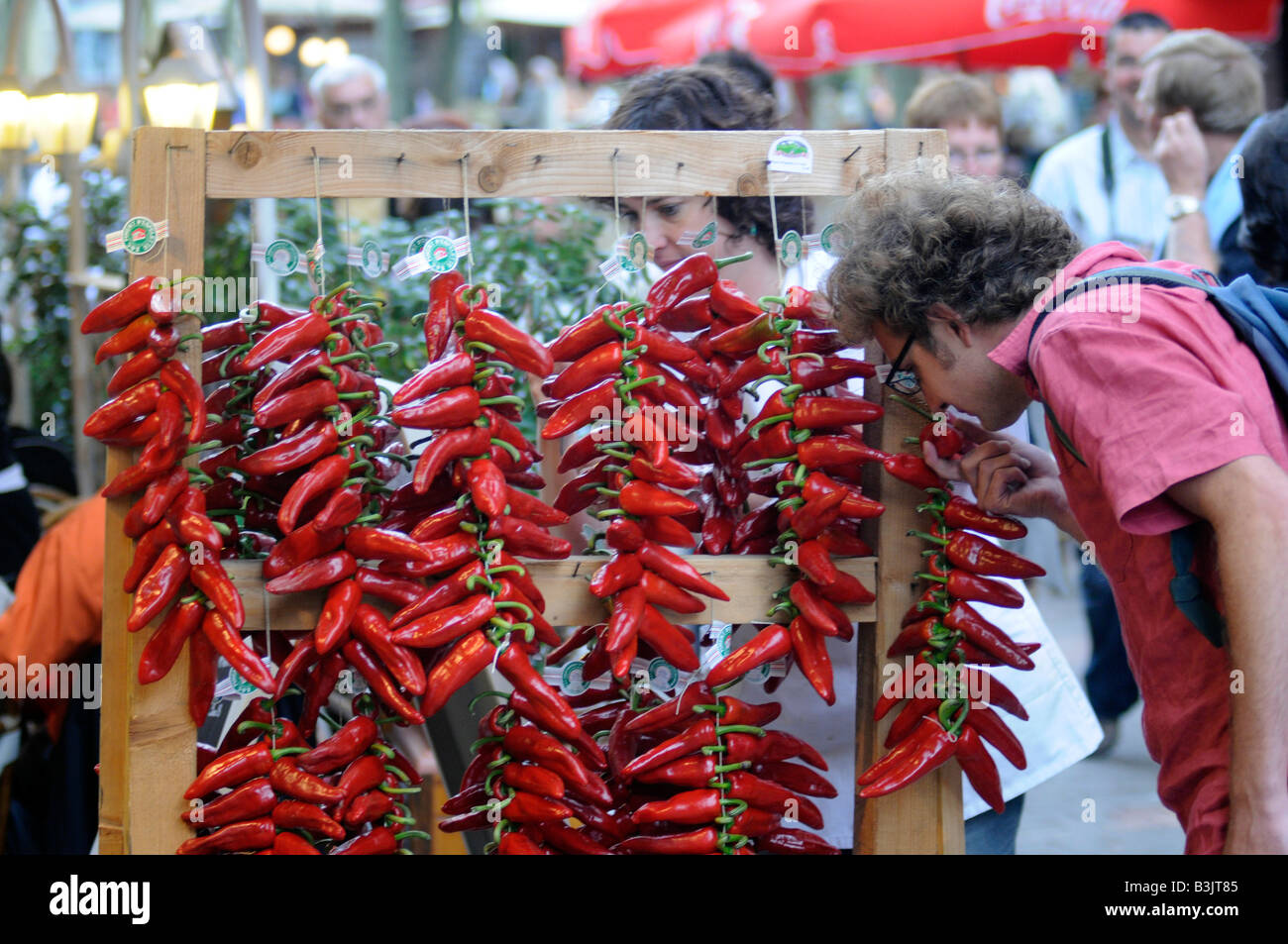 A French customer checking and smelling chili peppers for sale in Saint ...
