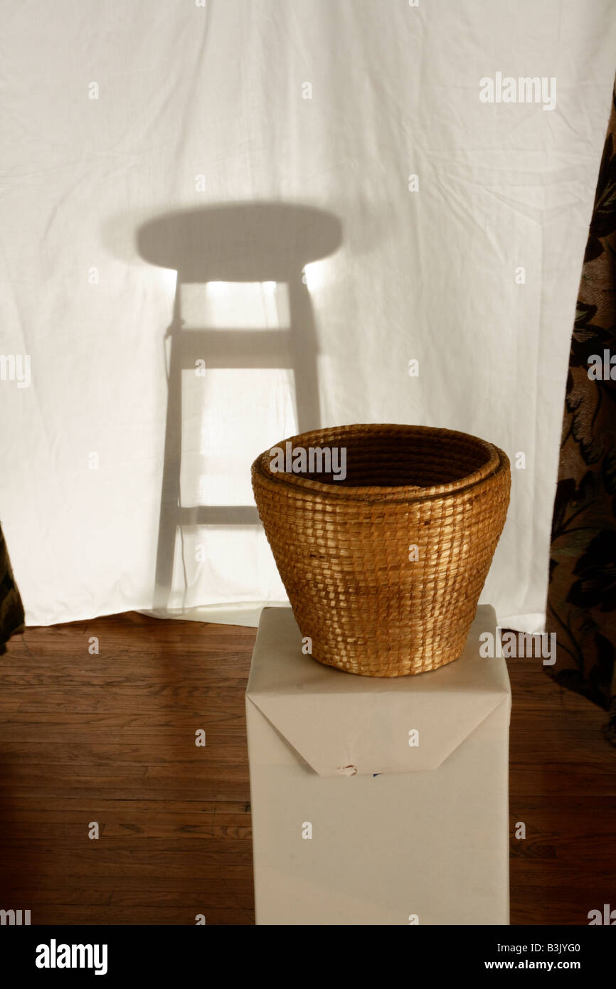 Handmade basket on pedestal in front of shadow of stool Stock Photo - Alamy