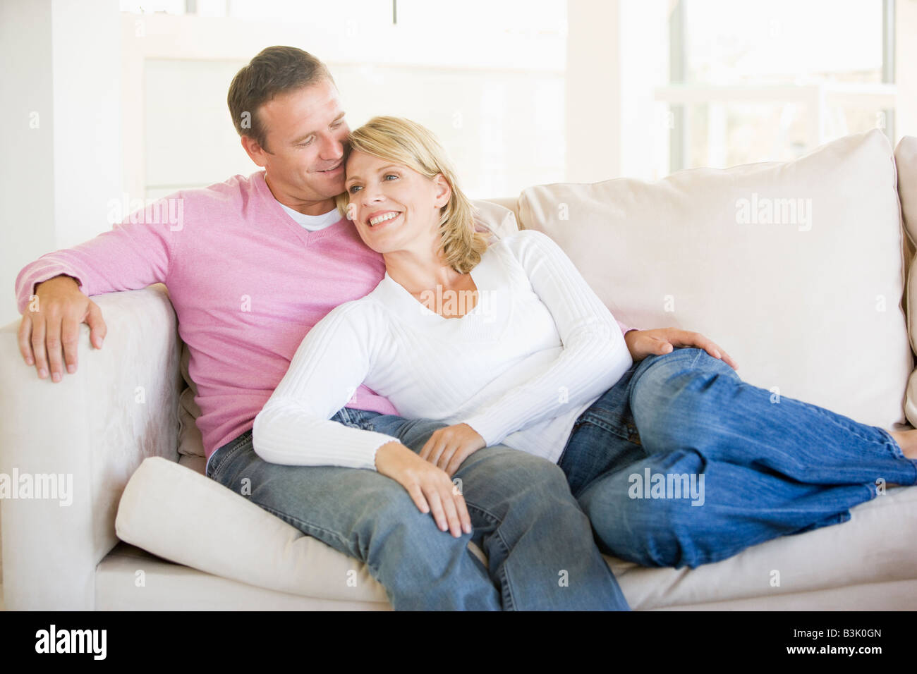 Couple relaxing in living room and smiling Stock Photo - Alamy