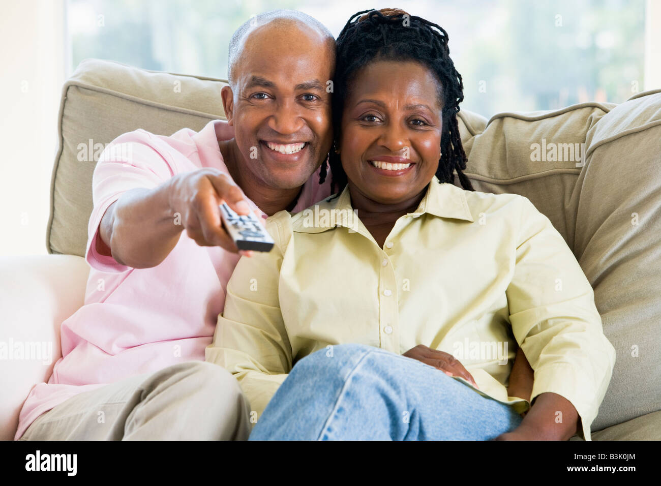 Couple relaxing in living room holding remote control and smiling Stock ...