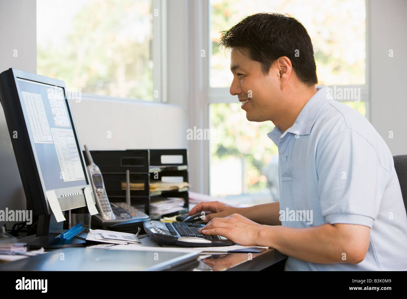 Man in home office using computer and smiling Stock Photo - Alamy