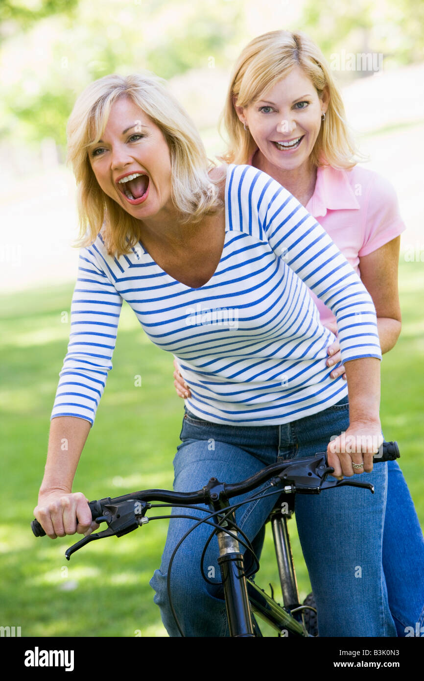 Two friends on one bike outdoors smiling Stock Photo - Alamy