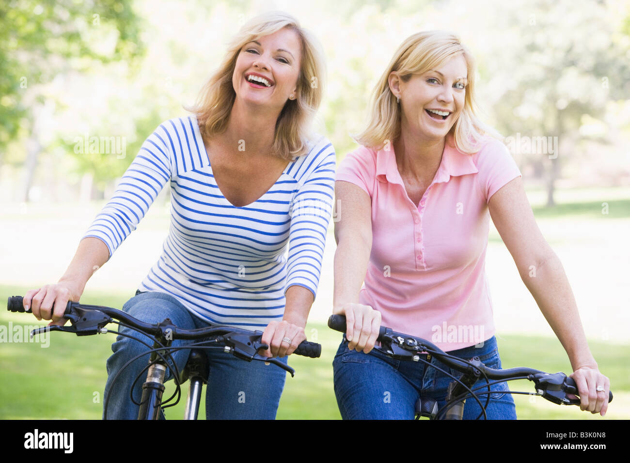 Two friends on bikes outdoors smiling Stock Photo - Alamy