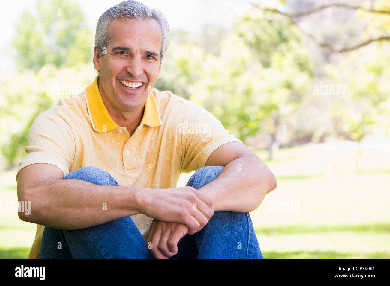 Man sitting outdoors smiling Stock Photo - Alamy