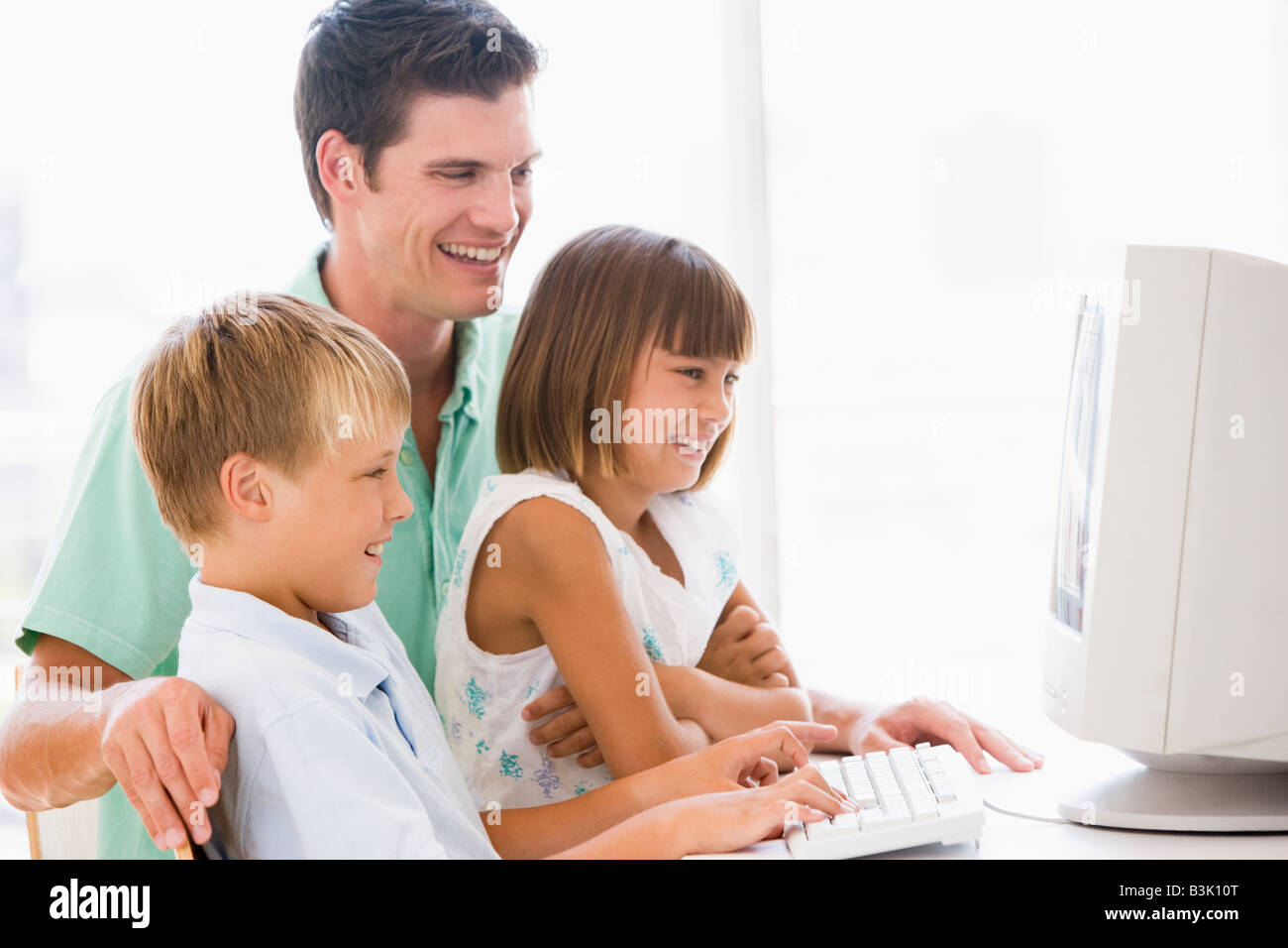 Man and two young children in home office with computer smiling Stock ...