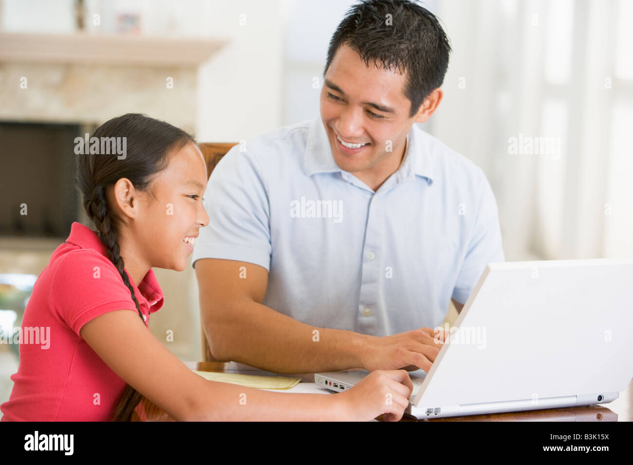 Man and young girl with laptop in dining room smiling Stock Photo - Alamy