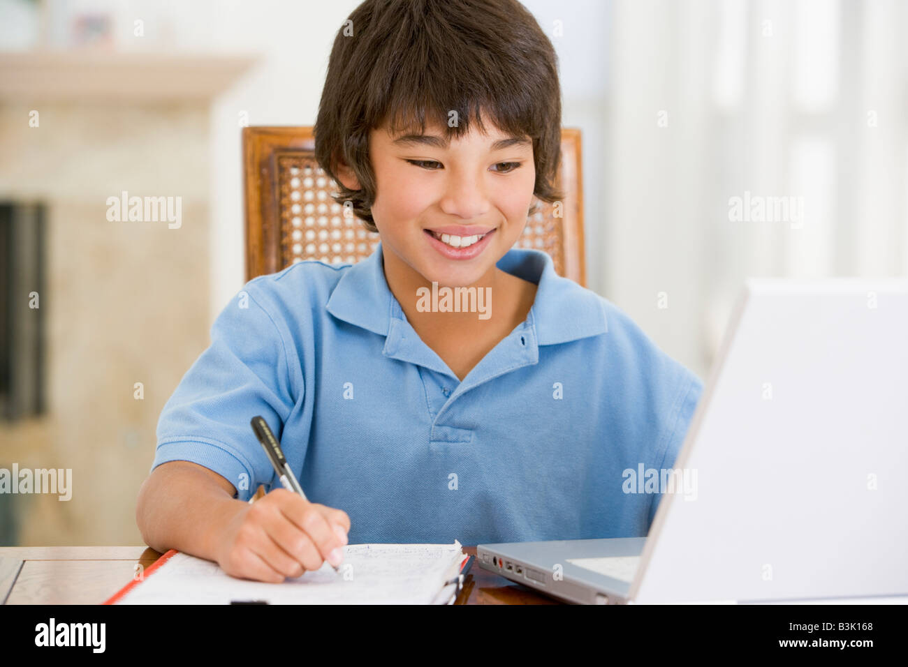 Young boy with laptop doing homework in dining room smiling Stock Photo ...