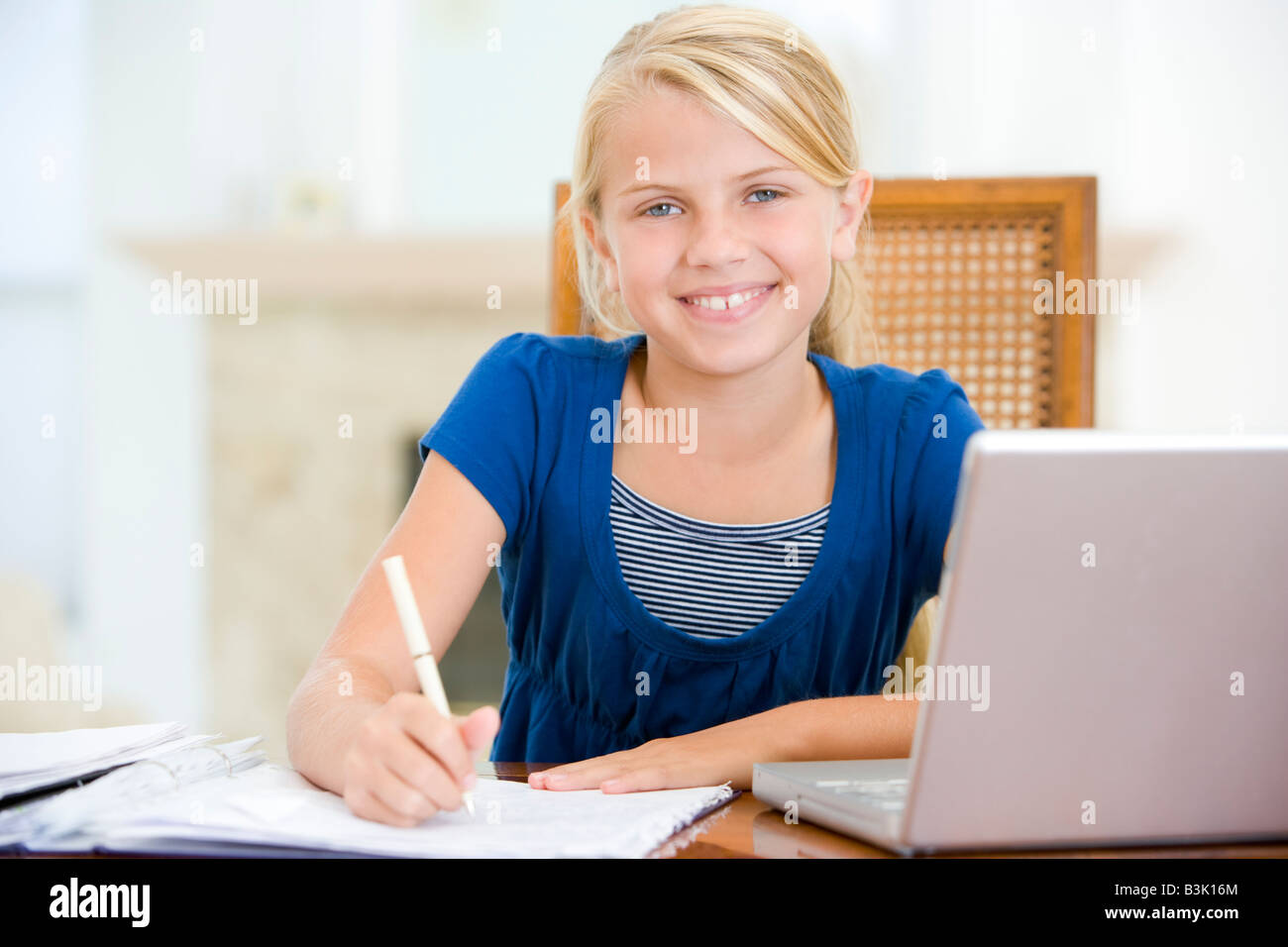Young girl with laptop doing homework in dining room smiling Stock ...