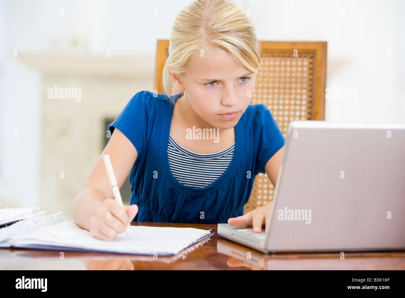 Young girl with laptop doing homework in dining room Stock Photo - Alamy