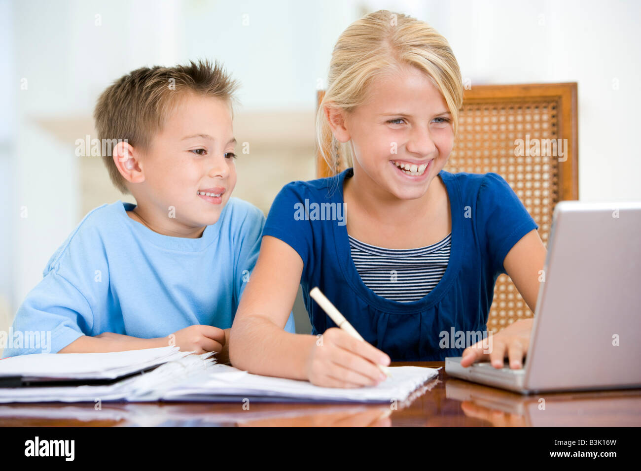 Two young children with laptop doing homework in dining room smiling ...