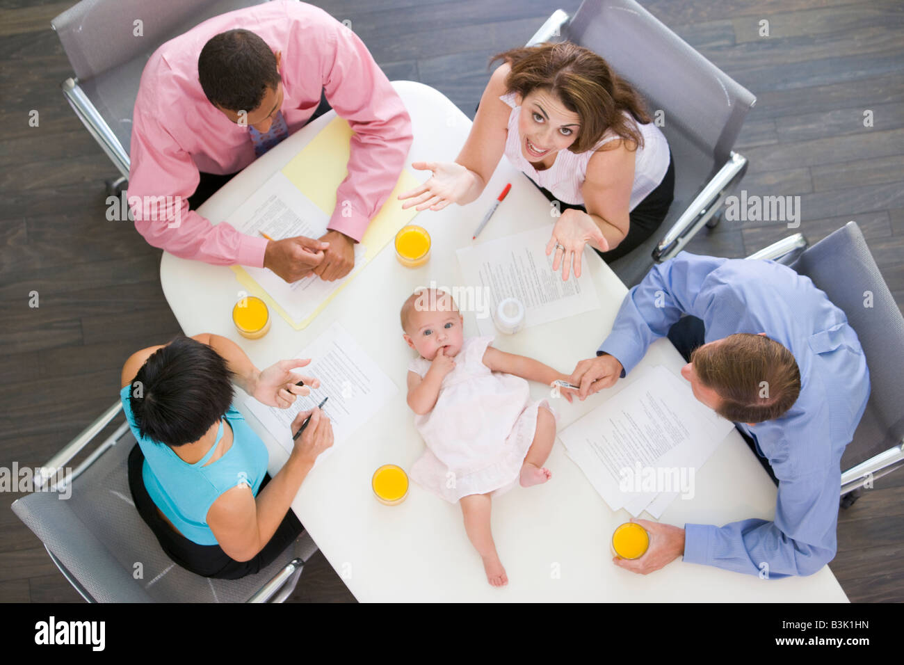 Four businesspeople in boardroom with a baby lying on the table Stock ...