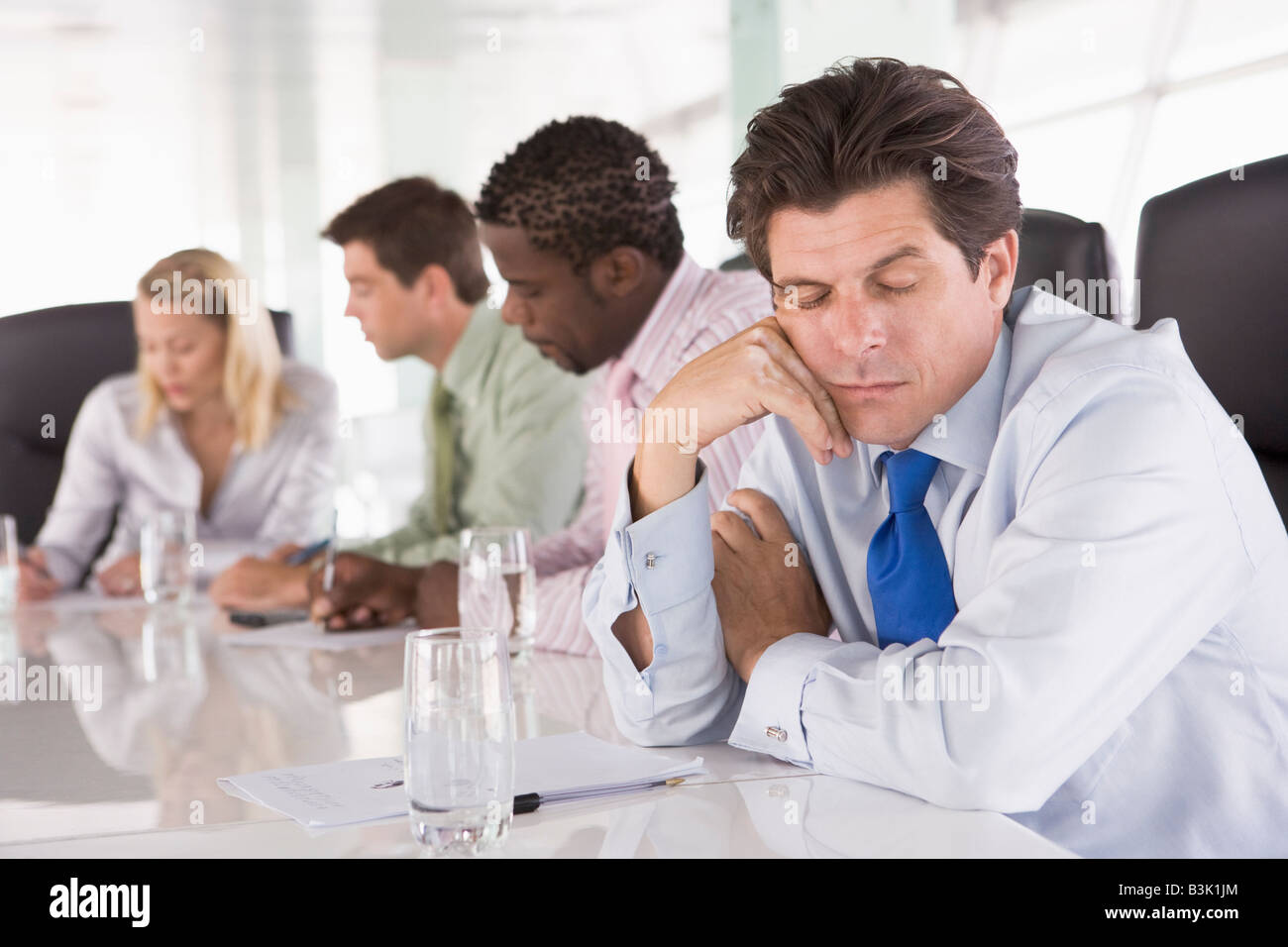Four businesspeople in boardroom with one businessman sleeping Stock ...