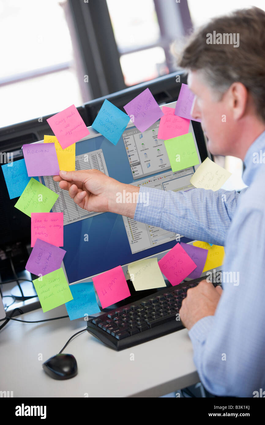 Businessman in office at monitor with notes on it Stock Photo - Alamy