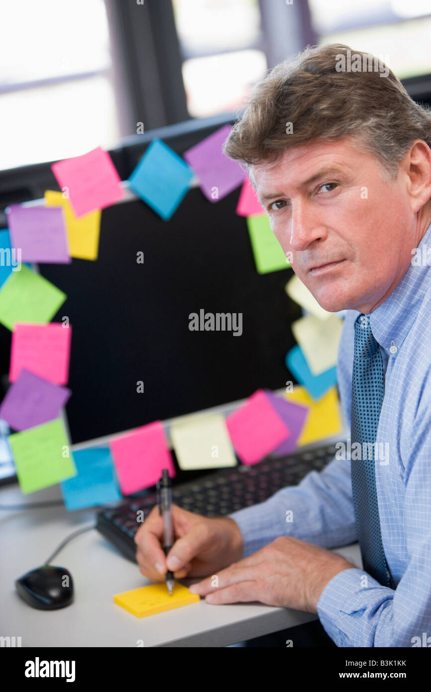 Businessman in office at monitor with notes on it writing Stock Photo ...