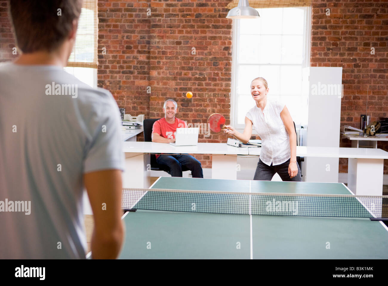 Man and woman in office space playing ping pong Stock Photo - Alamy