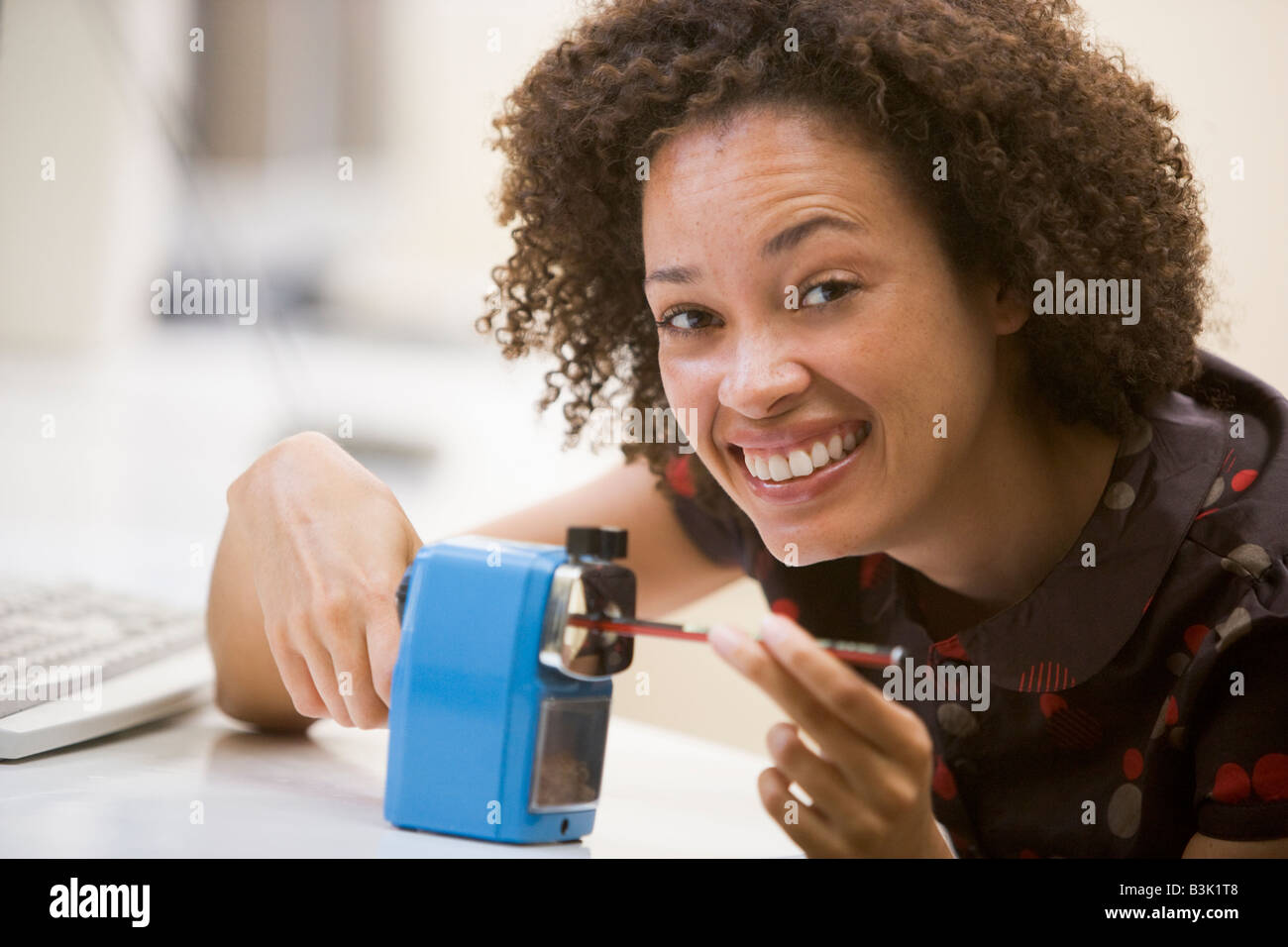 Woman in computer room using pencil sharpener and smiling Stock Photo ...