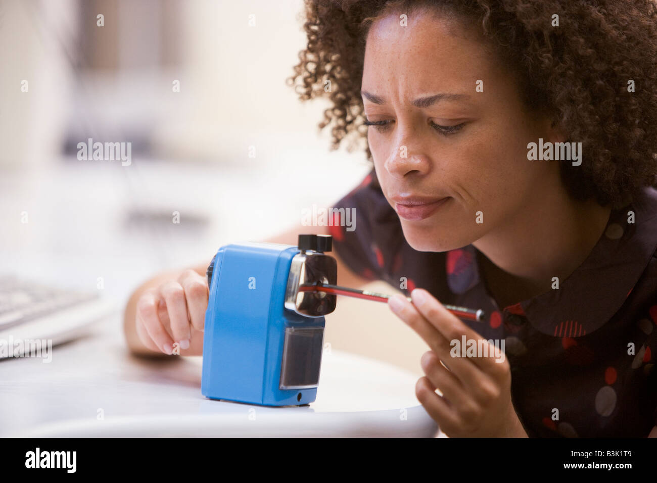 Woman in computer room using pencil sharpener Stock Photo - Alamy