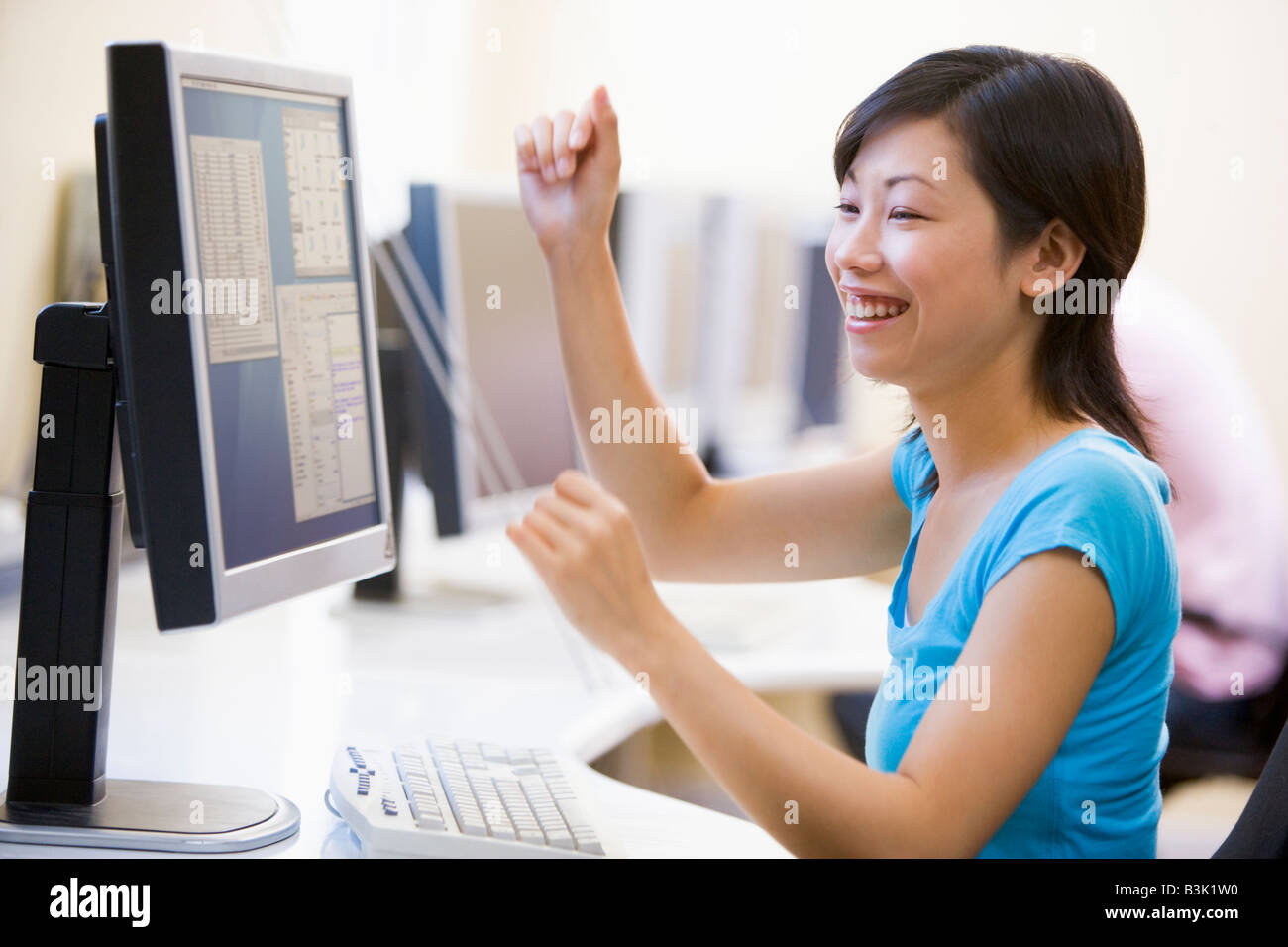 Woman in computer room cheering and smiling Stock Photo - Alamy