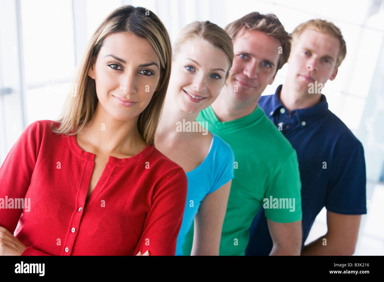Four people standing in corridor smiling Stock Photo - Alamy