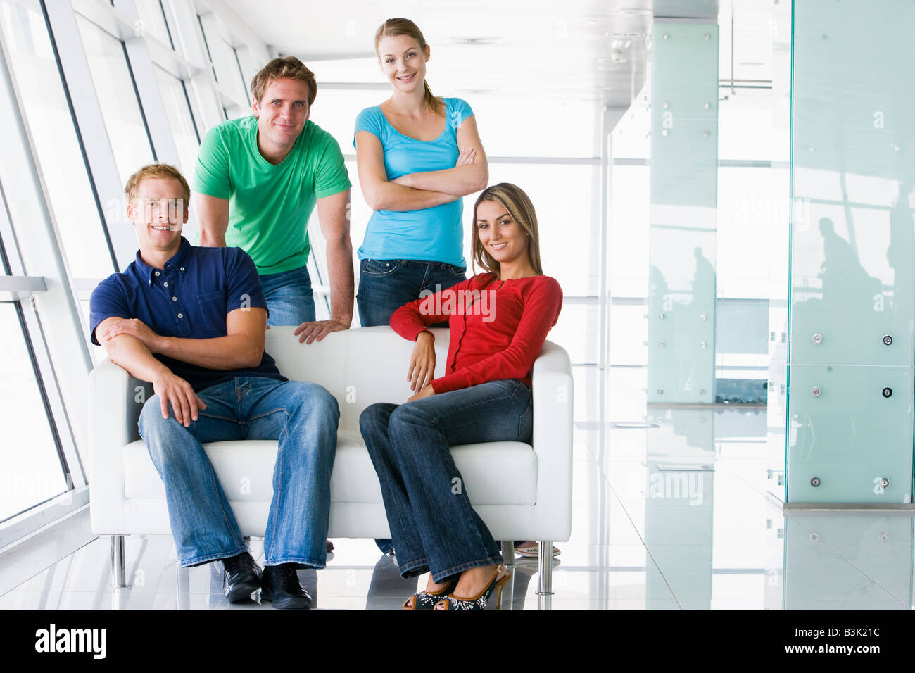 Four people in lobby smiling Stock Photo - Alamy