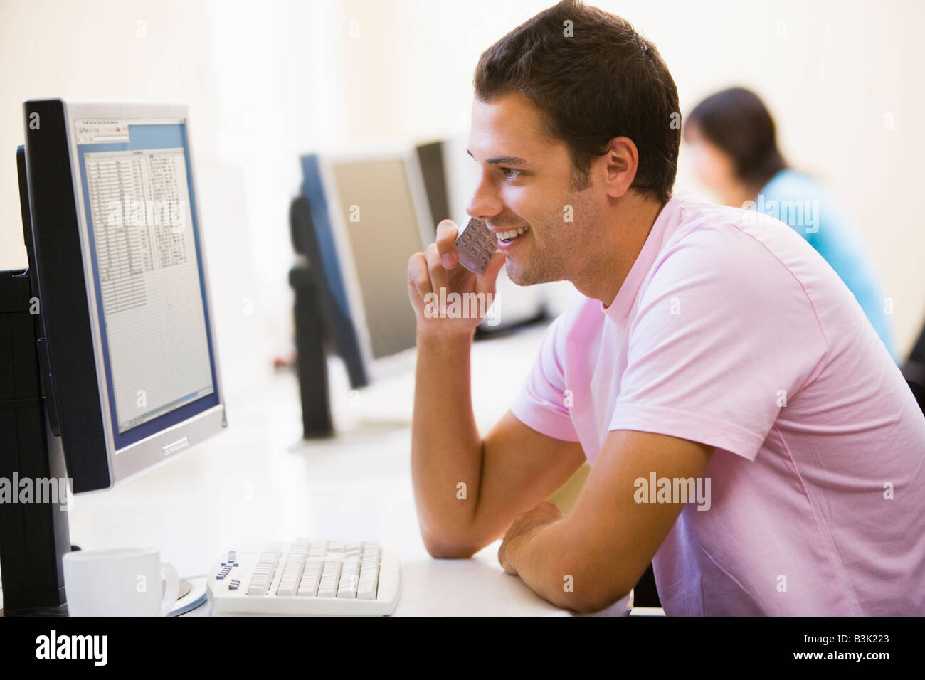Man in computer room using cellular phone and smiling Stock Photo - Alamy