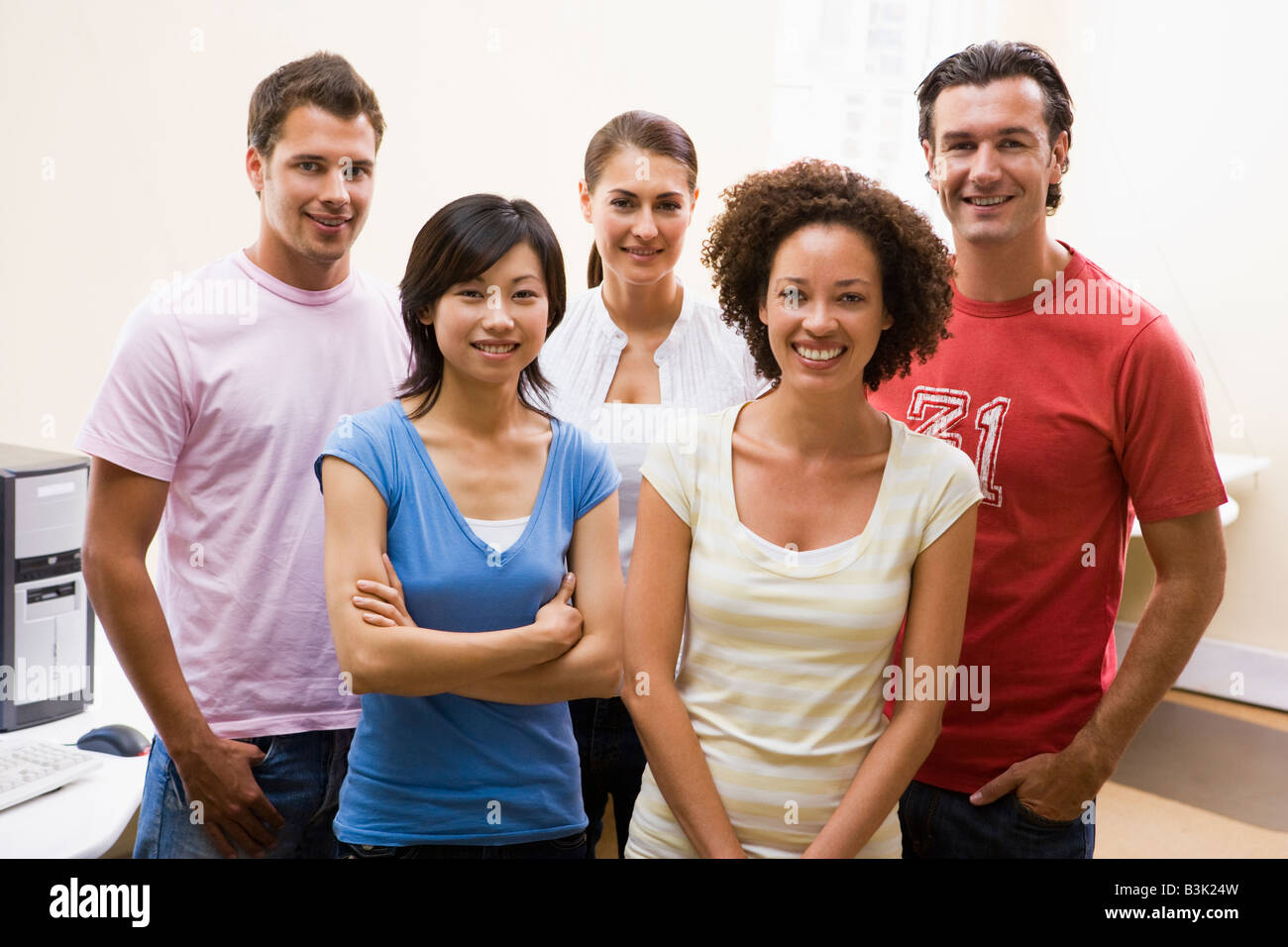 Five people standing in computer room smiling Stock Photo - Alamy