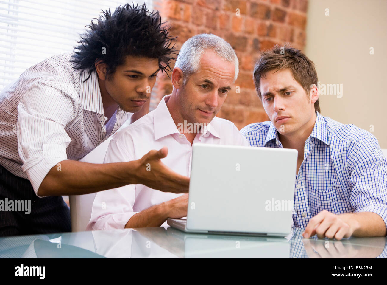 Three businessmen sitting in office with laptop Stock Photo - Alamy