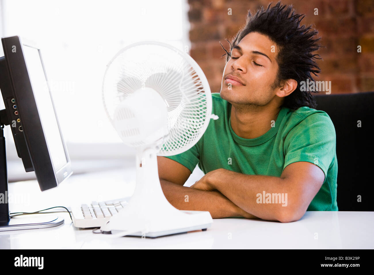 Businessman in office with computer and fan cooling off Stock Photo - Alamy