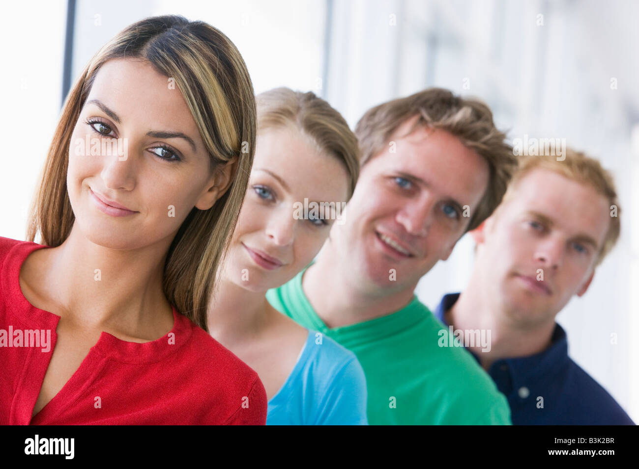 Four people standing in corridor smiling Stock Photo - Alamy