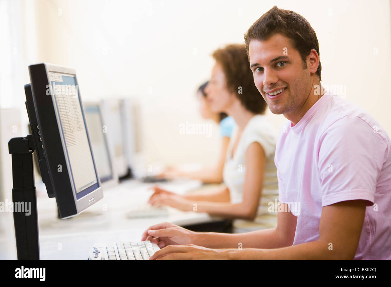 Three people sitting in computer room typing and smiling Stock Photo ...